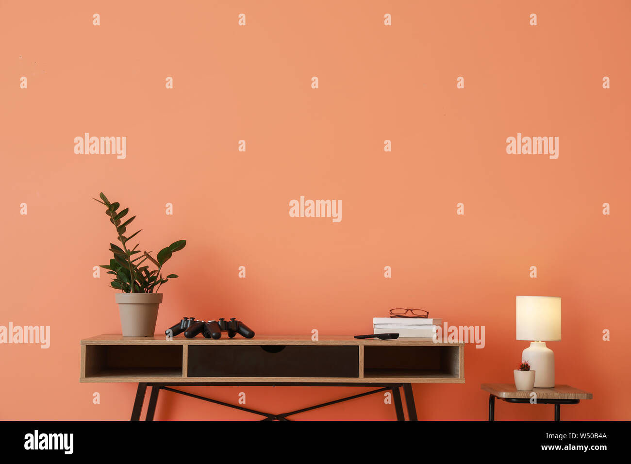 Modern table near color wall Stock Photo - Alamy