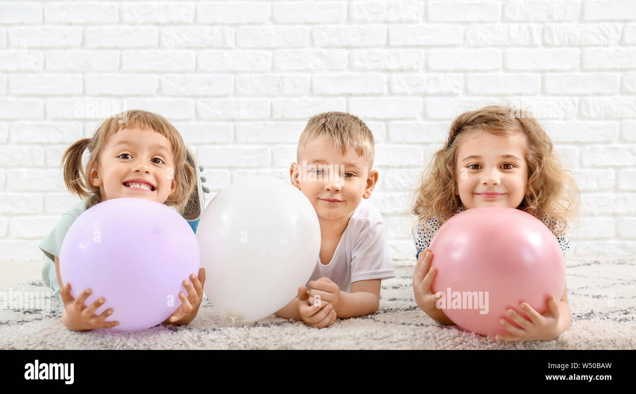 Cute little children with air balloons lying on floor Stock Photo - Alamy