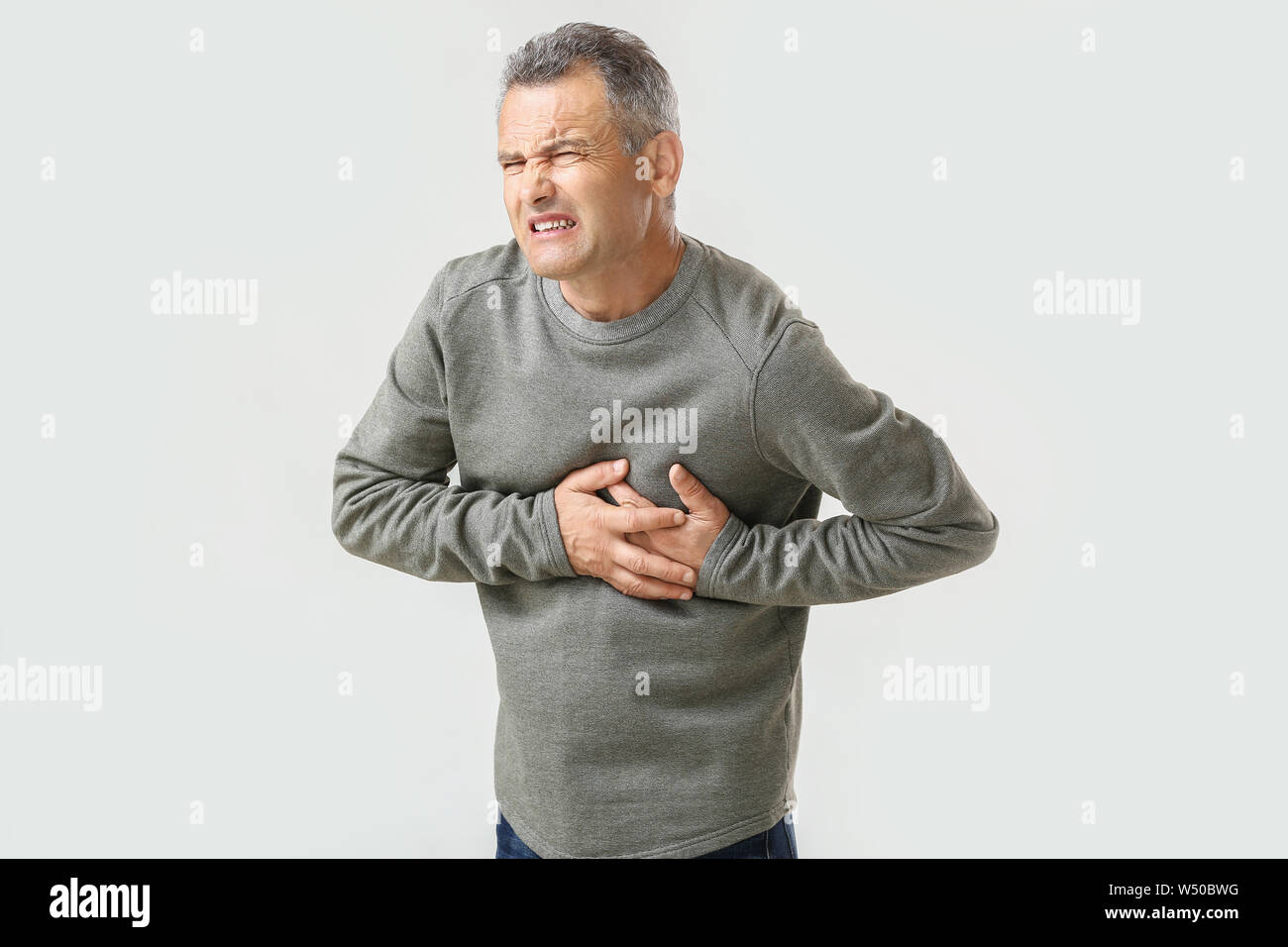 Mature man suffering from heart attack on white background Stock Photo ...