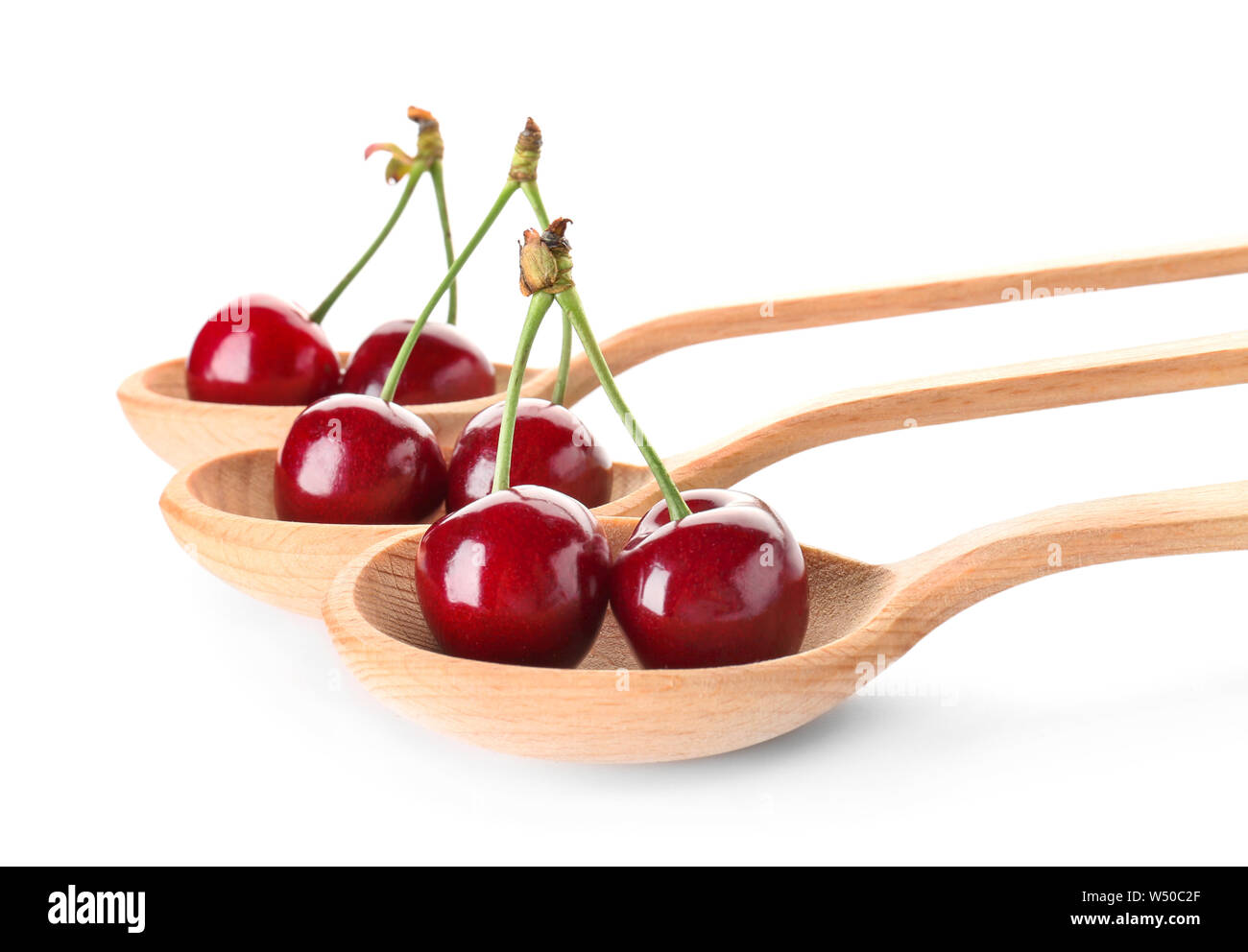 Spoons with sweet ripe cherry on white background Stock Photo - Alamy