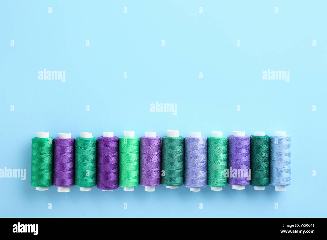 Many sewing threads on color background Stock Photo - Alamy