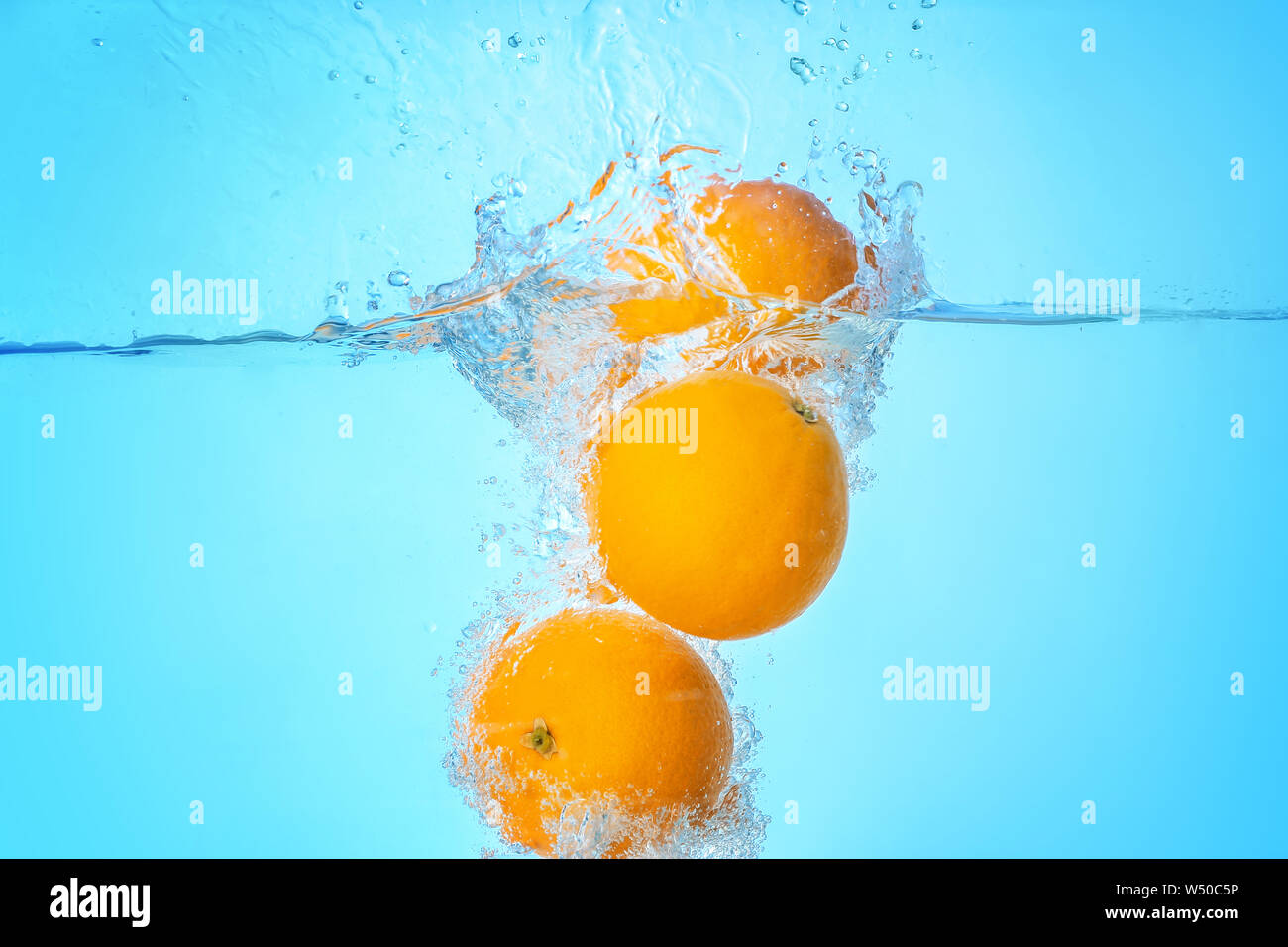 Falling of oranges into water on light background Stock Photo - Alamy