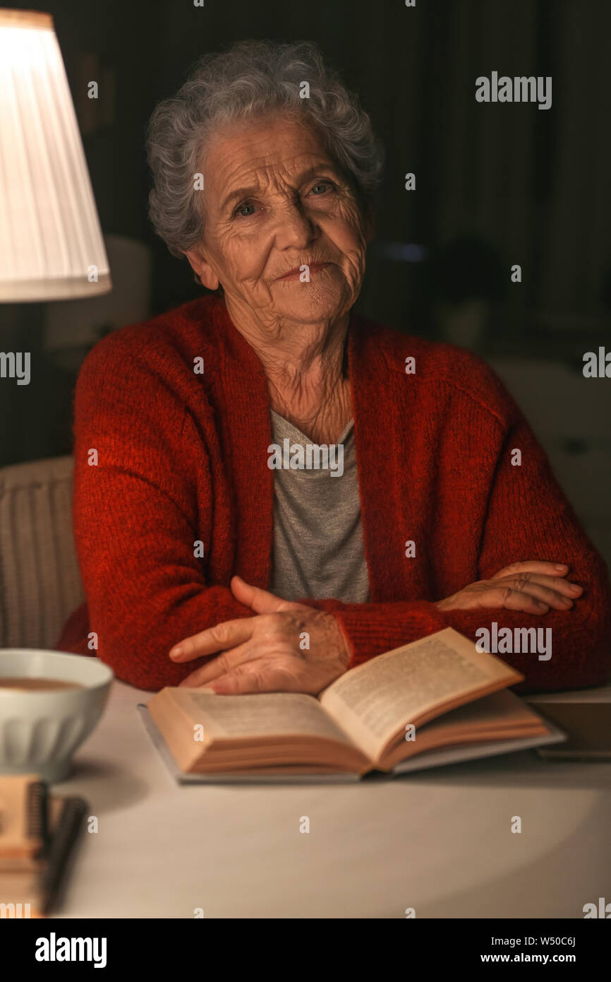 Senior woman reading book at night Stock Photo - Alamy