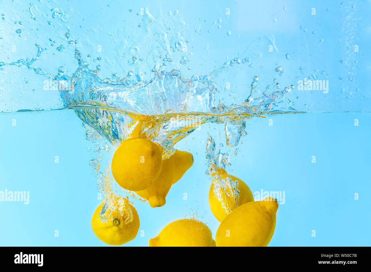 Falling of lemons into water on light background Stock Photo - Alamy