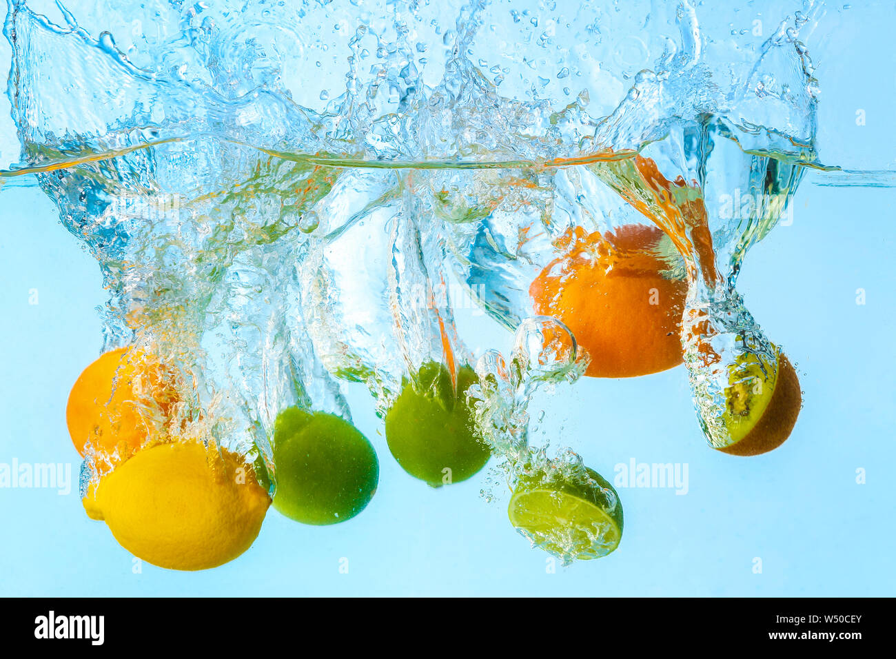 Falling of different fruits into water on light background Stock Photo ...