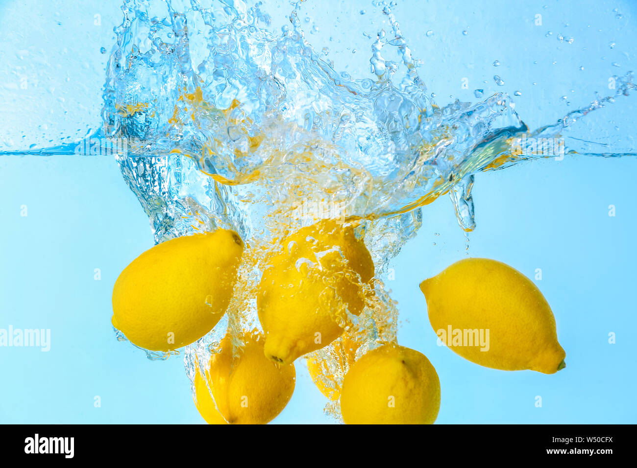 Falling of lemons into water on light background Stock Photo - Alamy
