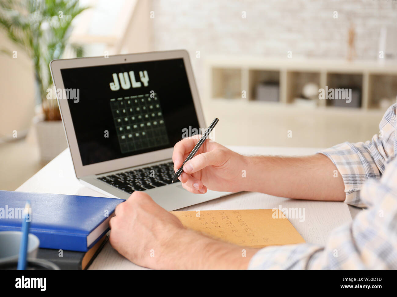 Man using calendar on laptop screen while working in office Stock Photo ...