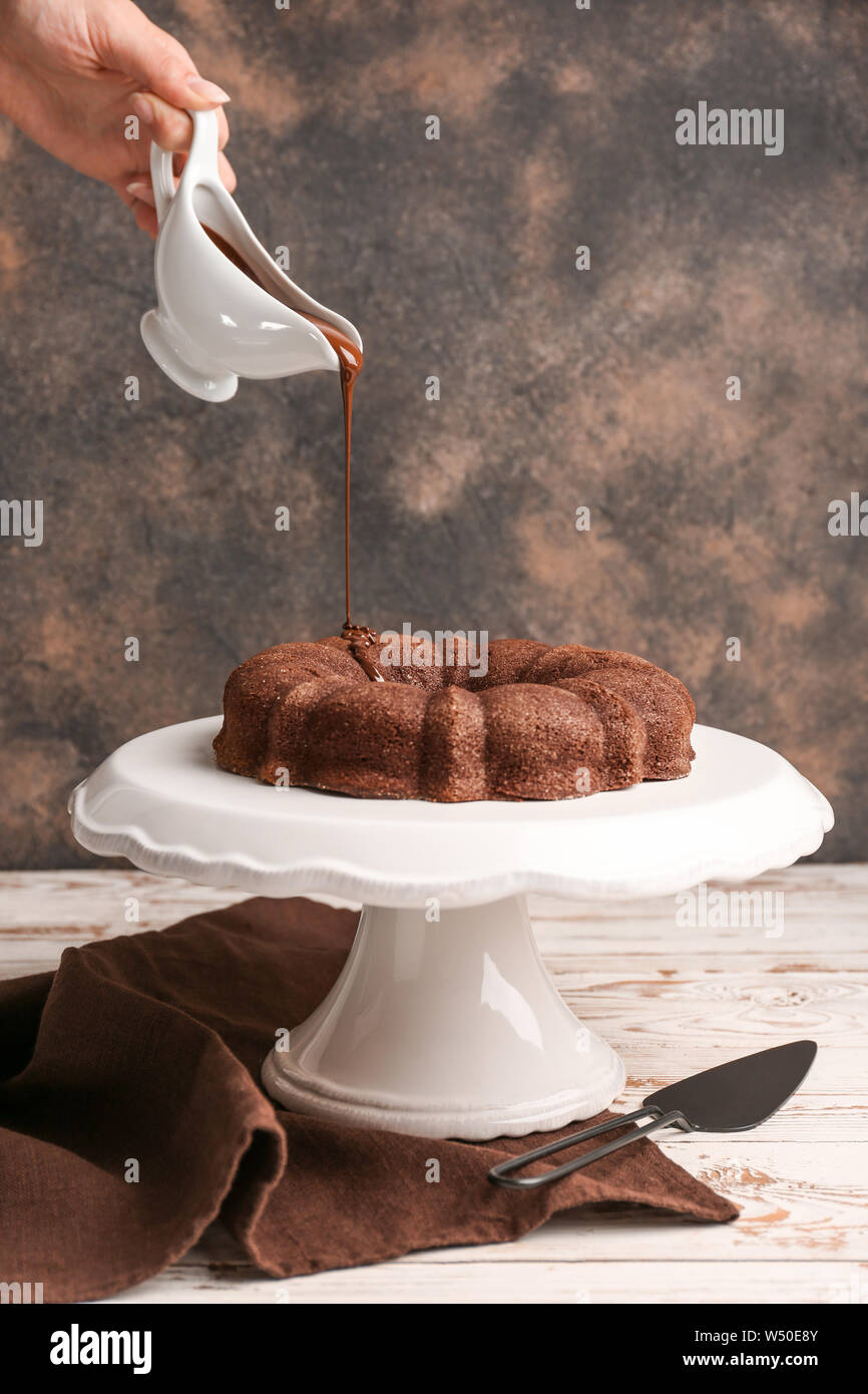 Woman pouring chocolate sauce on tasty cake Stock Photo - Alamy