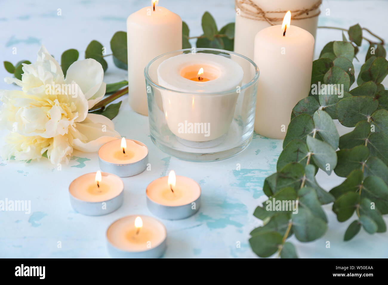 Beautiful burning candles with eucalyptus on light background Stock ...