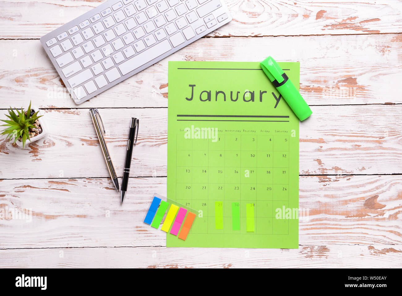Paper calendar, PC keyboard and stationery on light wooden background ...