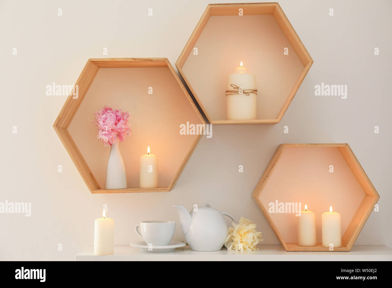 Wooden shelves with beautiful burning candles on light wall Stock Photo ...