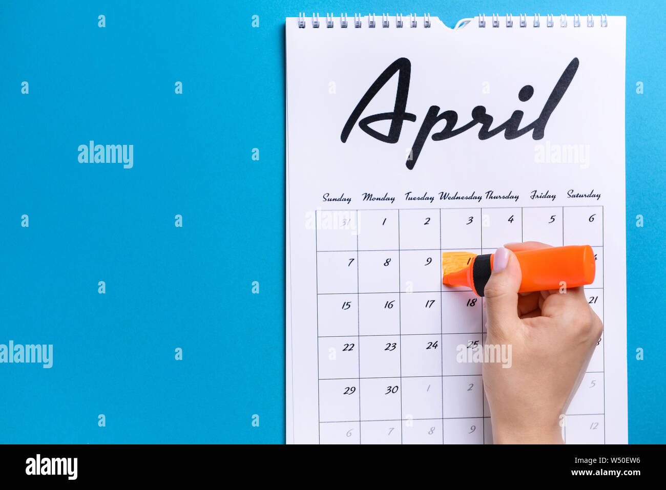 Woman marking date in calendar on color background Stock Photo - Alamy