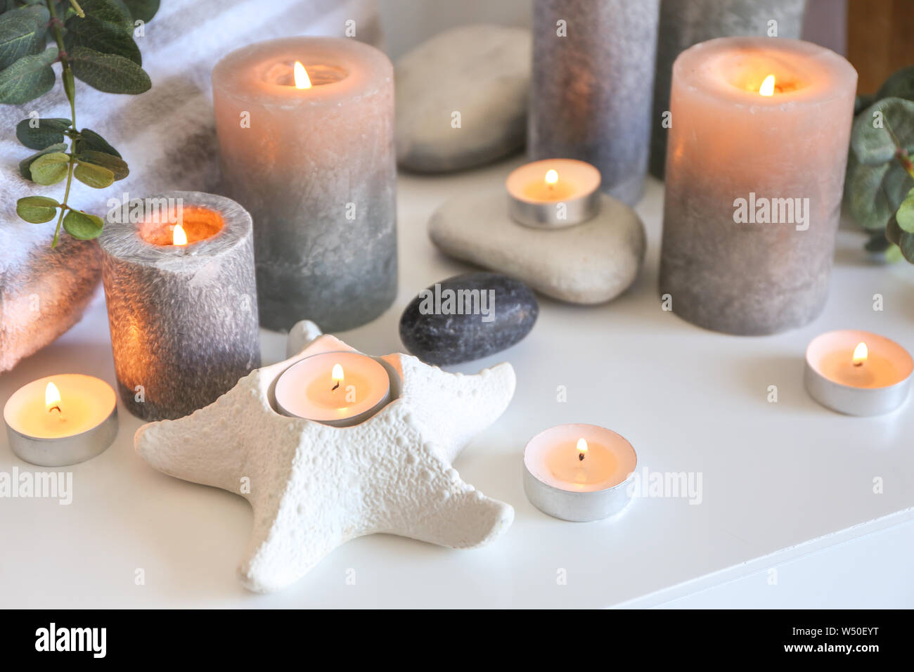 Beautiful burning candles on table in room Stock Photo - Alamy