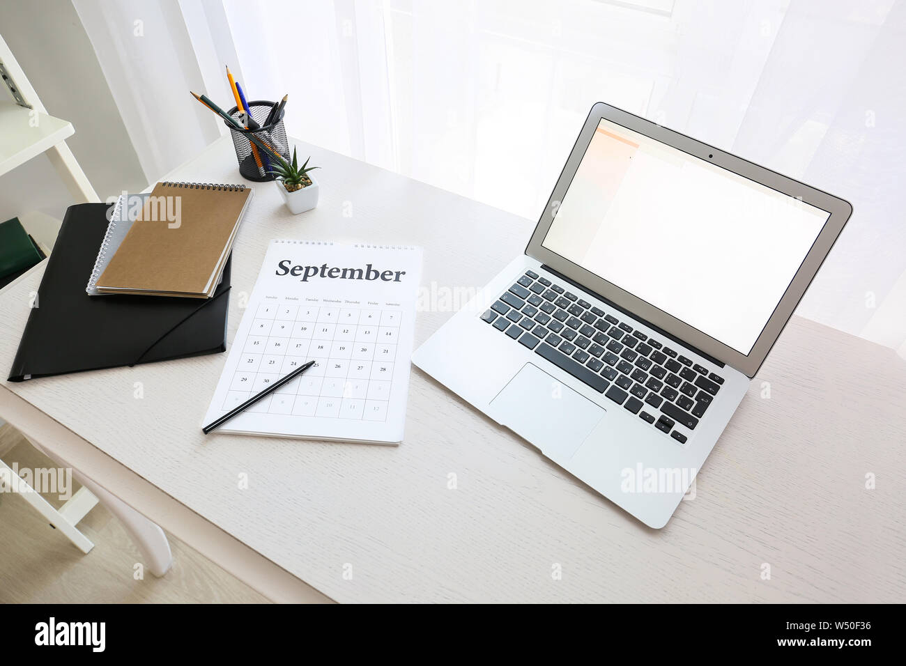 Flip calendar with laptop on table in room Stock Photo - Alamy