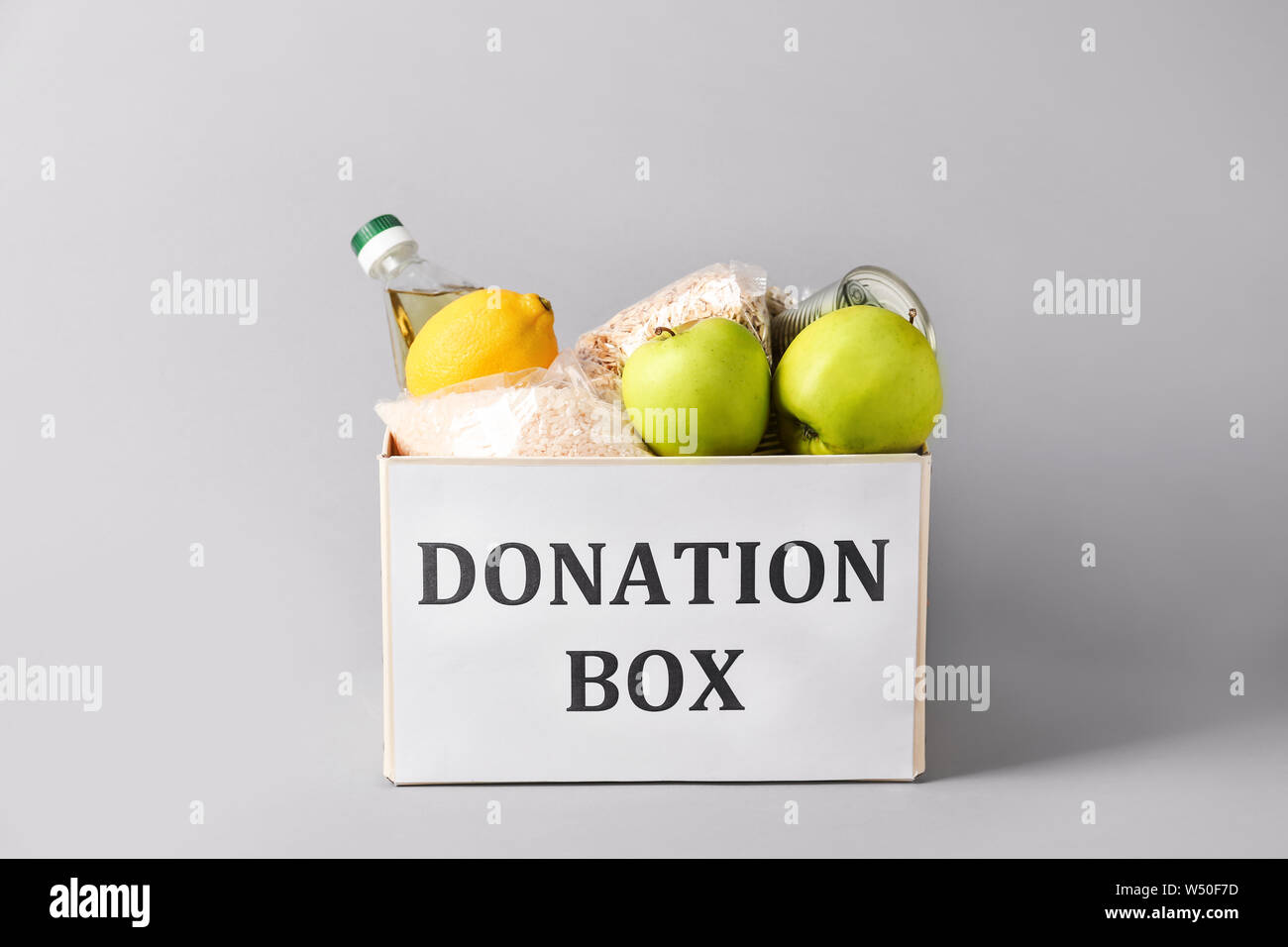 Box with donation food on grey background Stock Photo - Alamy