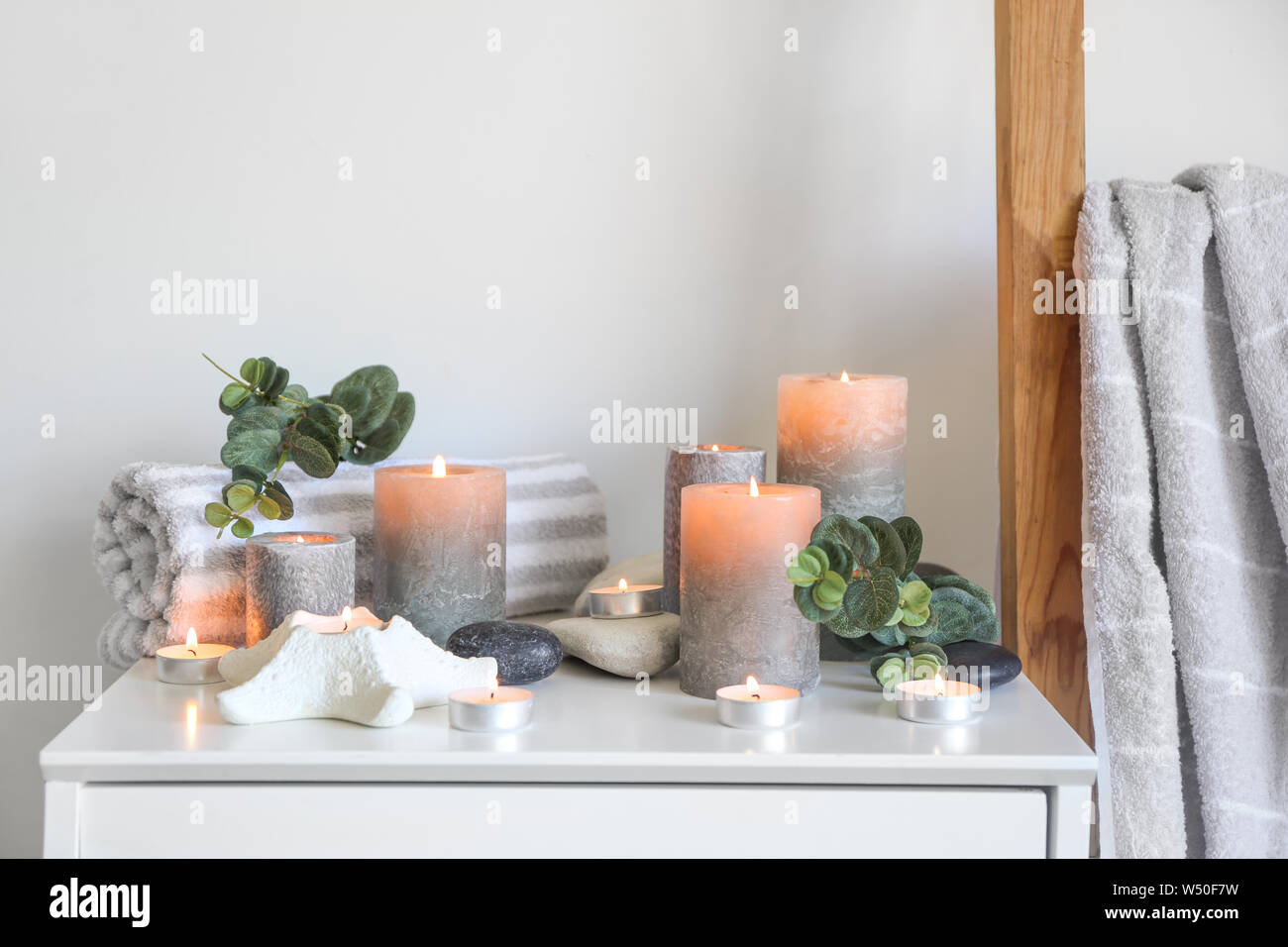 Beautiful burning candles with eucalyptus on table in room Stock Photo ...