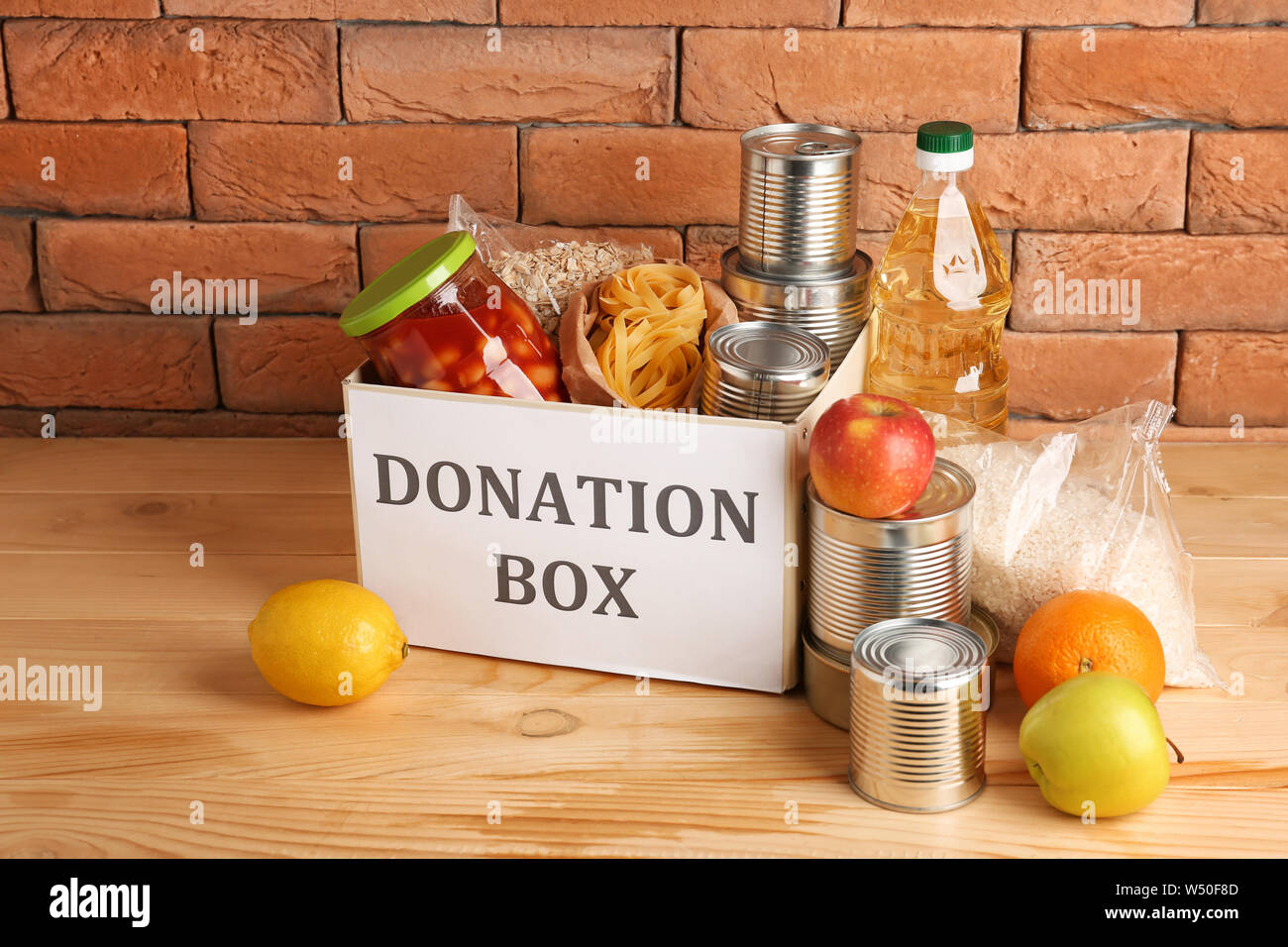 Box with donation food on table near brick wall Stock Photo - Alamy