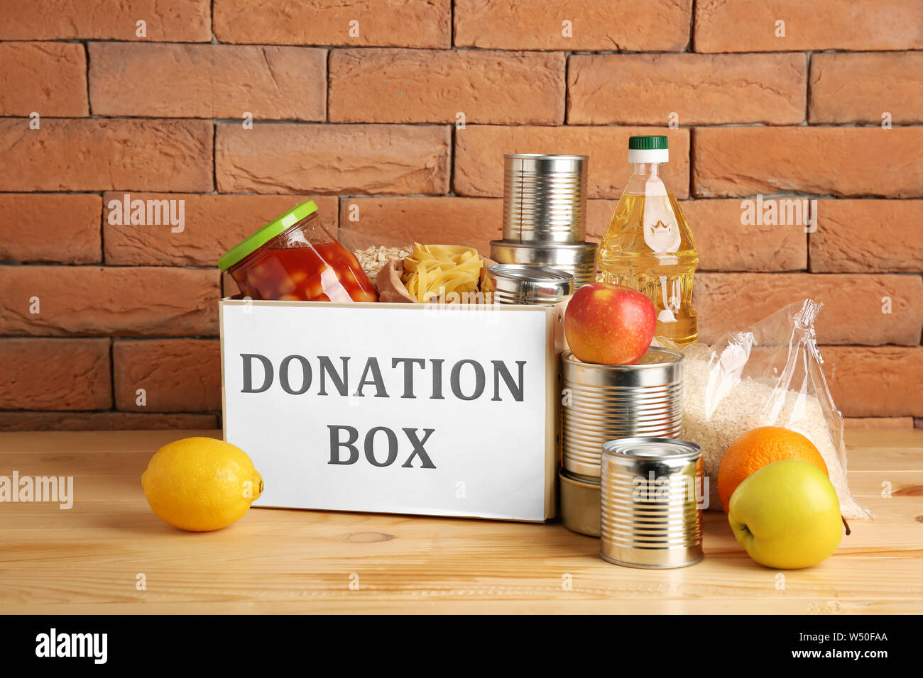 Box with donation food on table near brick wall Stock Photo - Alamy