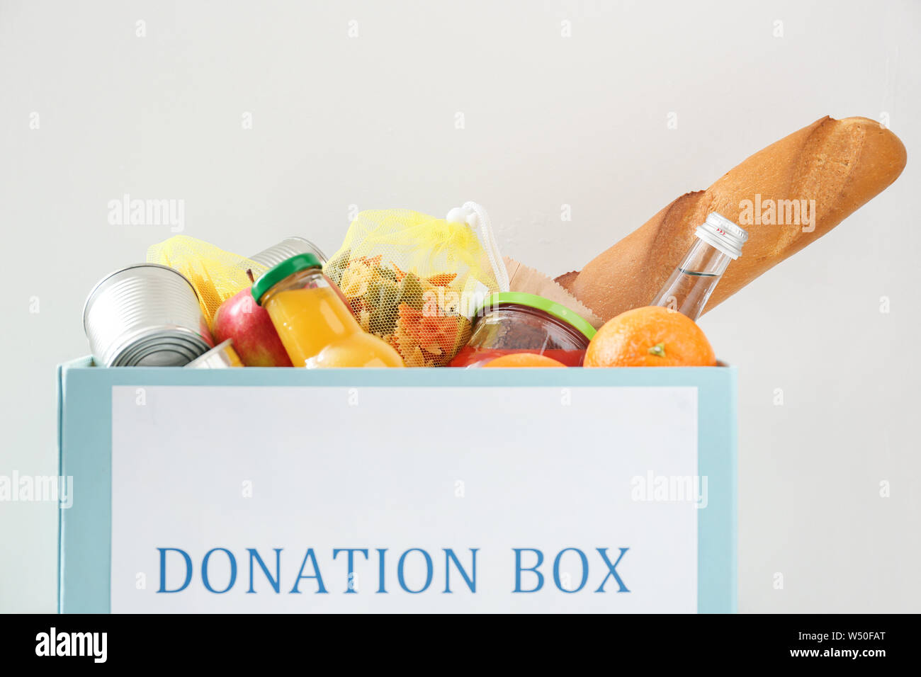 Box with donation food on light background Stock Photo - Alamy