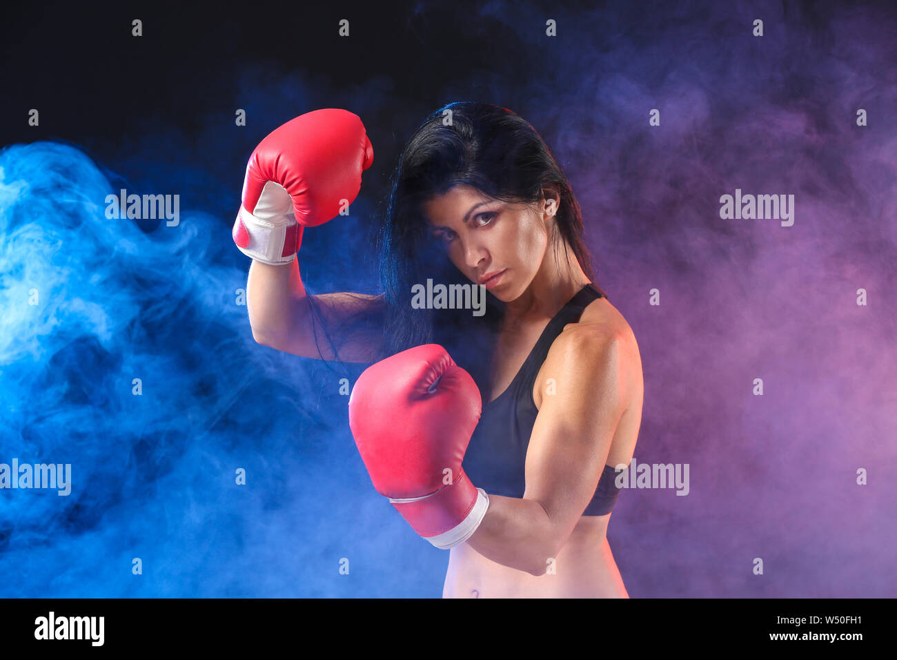 Sporty female boxer in smoke on dark background Stock Photo - Alamy