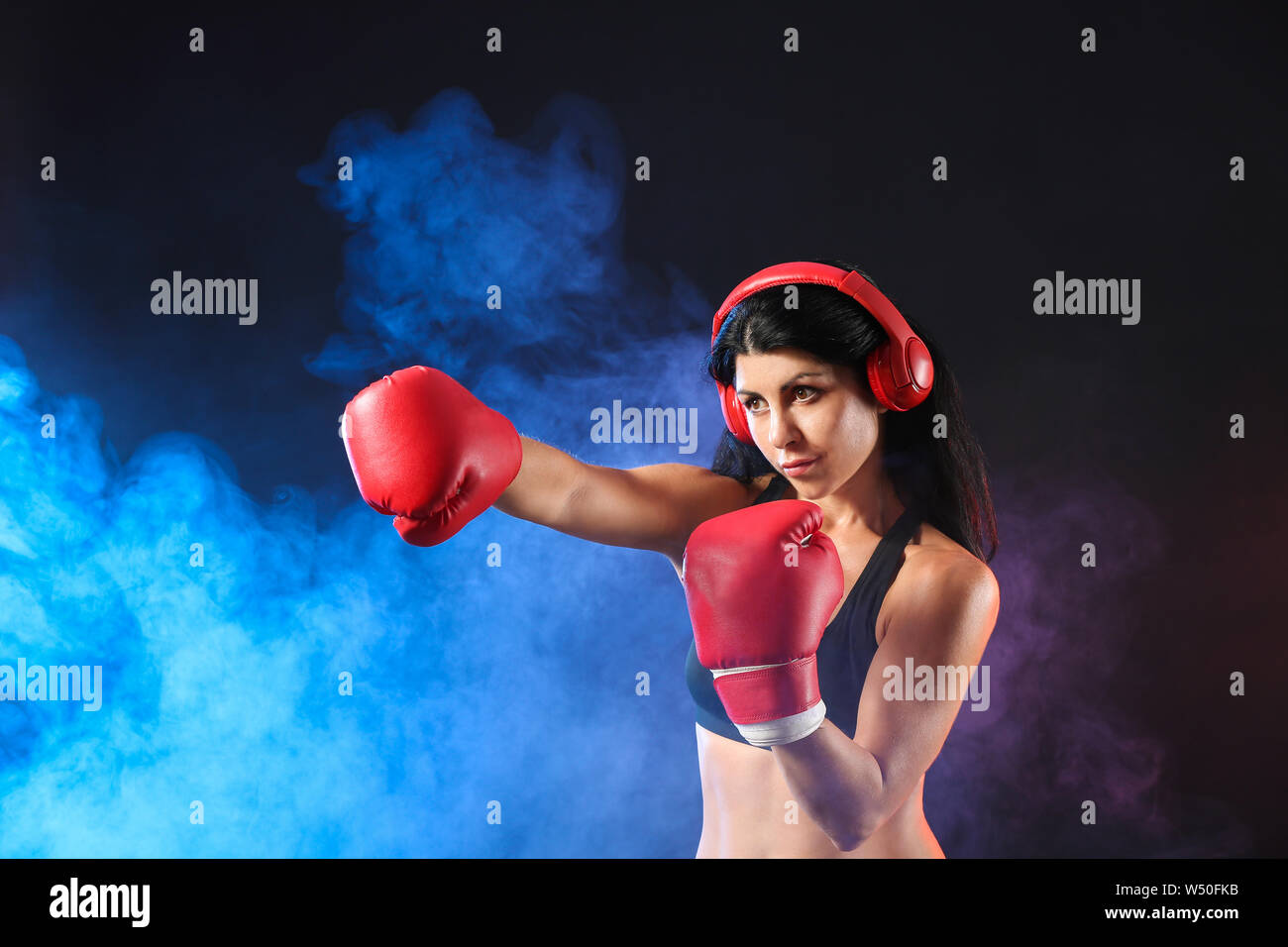 Sporty female boxer with headphones on dark background Stock Photo - Alamy