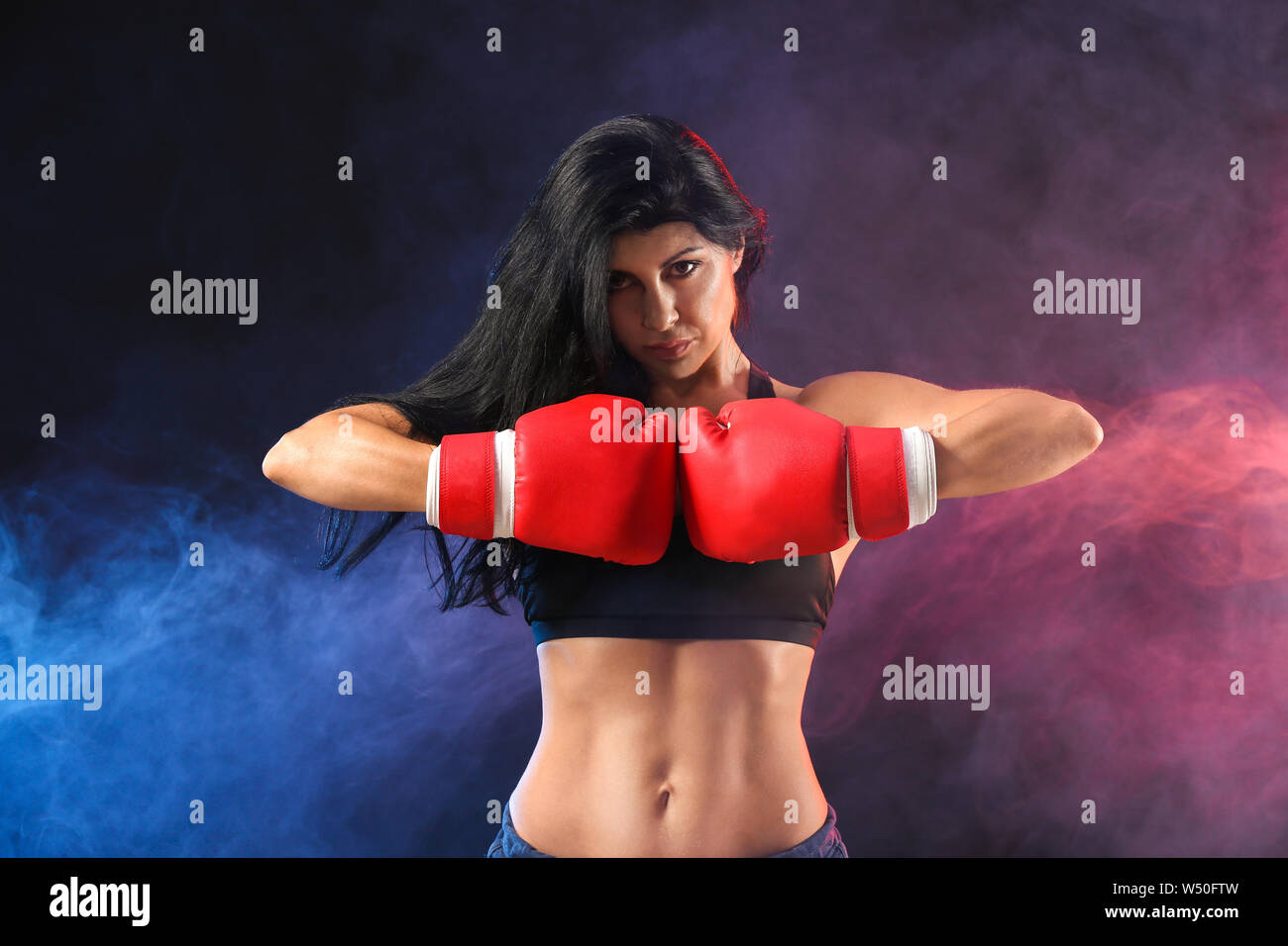 Sporty female boxer on dark background with color smoke Stock Photo - Alamy
