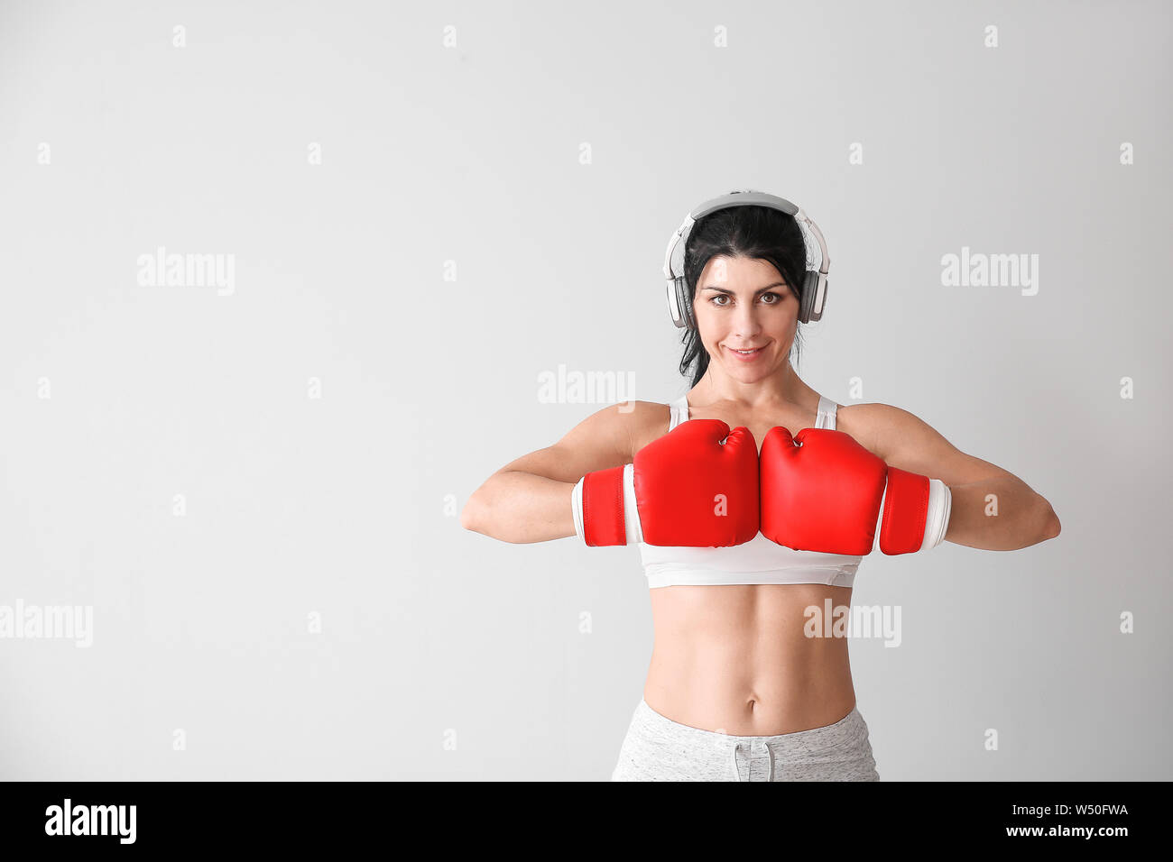 Sporty female boxer with headphones on white background Stock Photo - Alamy