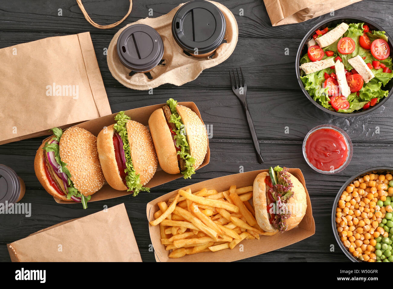 Different tasty food from delivery service on wooden background Stock ...