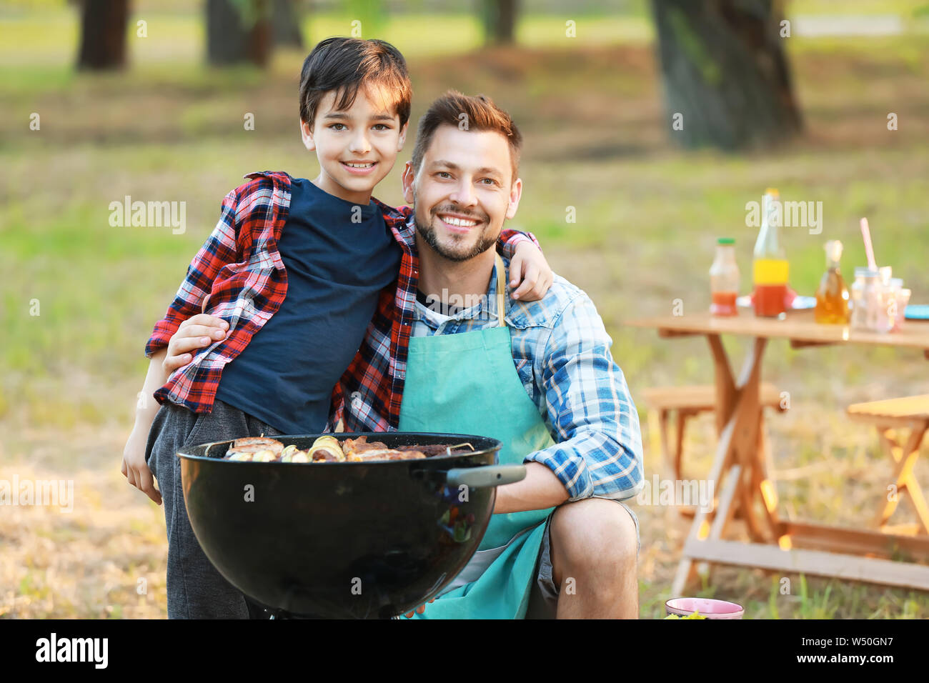 Little boy with father cooking tasty food on barbecue grill outdoors ...