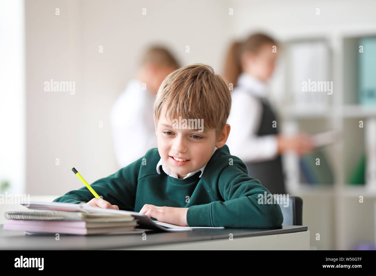 Cute little schoolboy doing lessons in classroom Stock Photo - Alamy