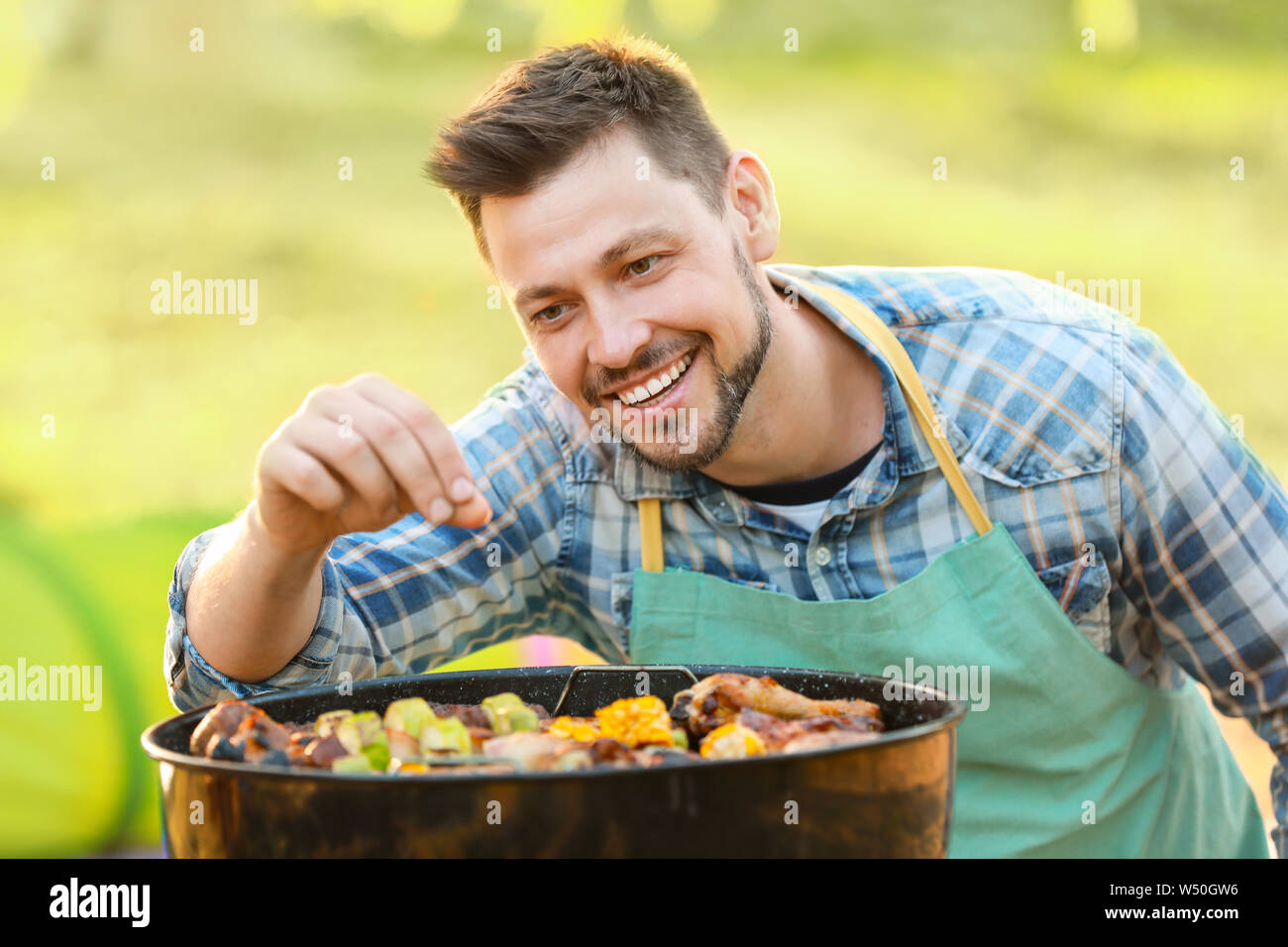 Man cooking tasty food on barbecue grill outdoors Stock Photo - Alamy