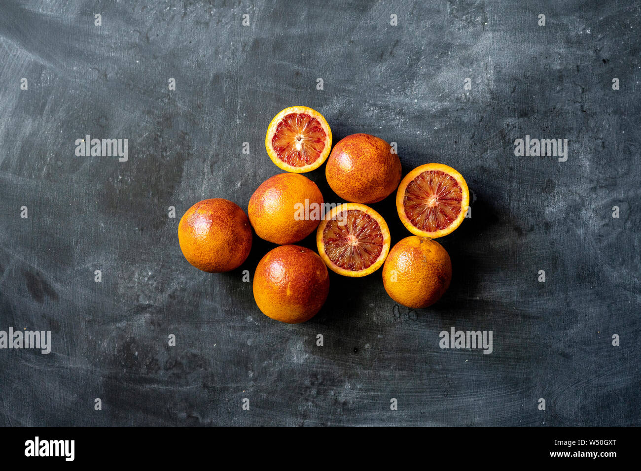 flat lay of red sliced exotic oranges, dark food on black surface Stock ...