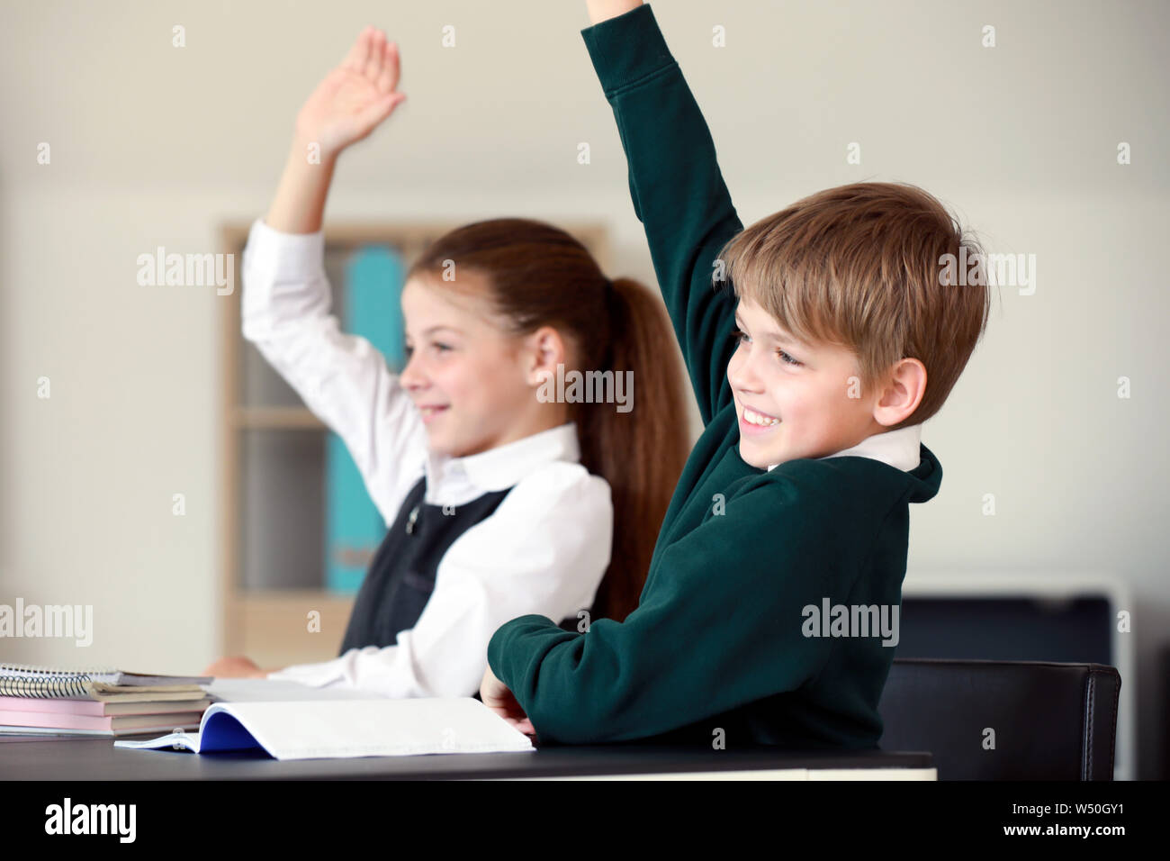 Cute little children raising hands during lesson in classroom Stock ...