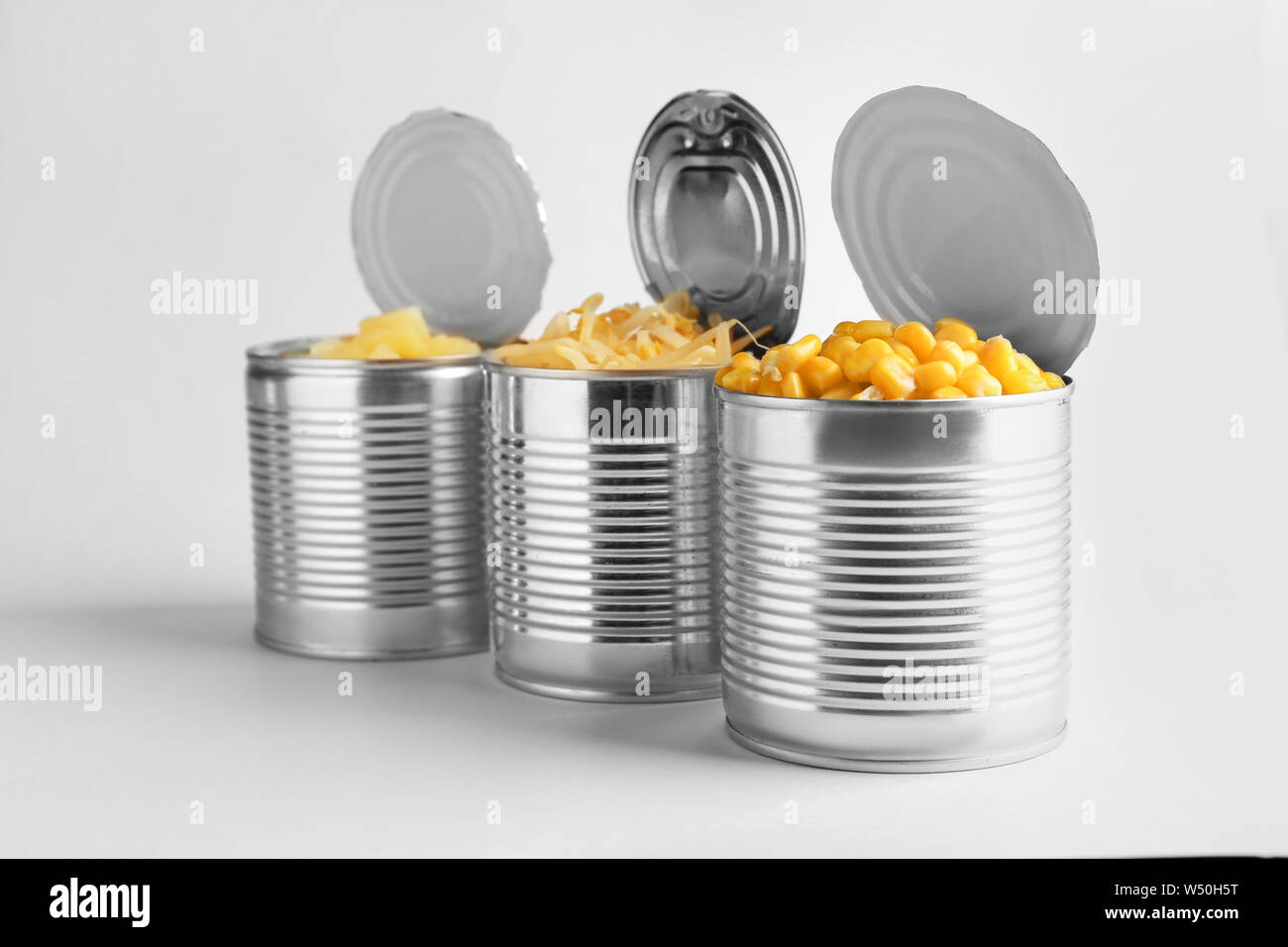 Tin cans with different food on light background Stock Photo - Alamy