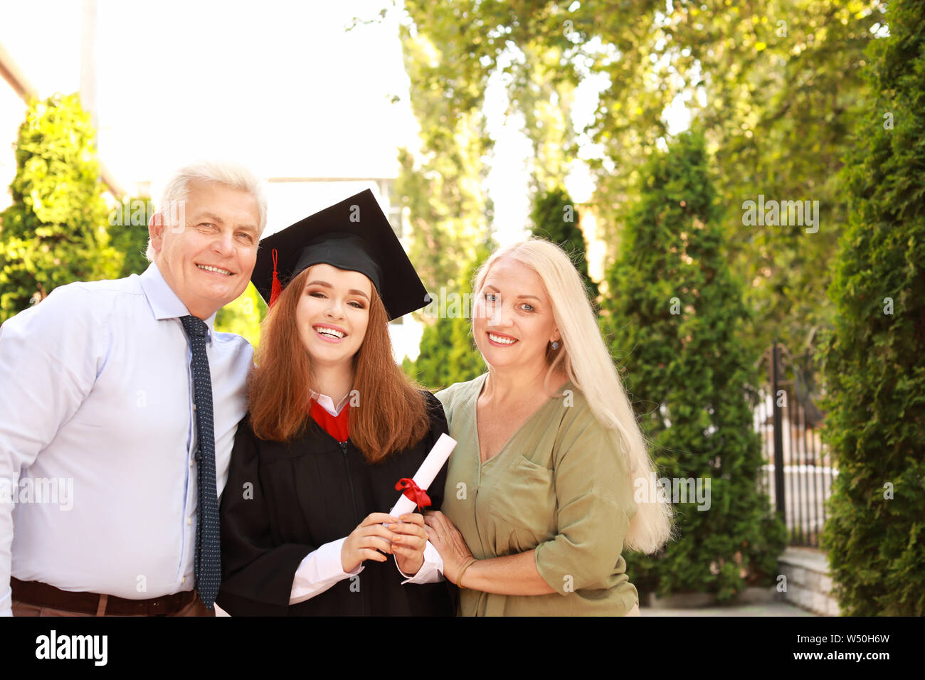 Happy young woman with diploma and her parents on graduation day Stock ...