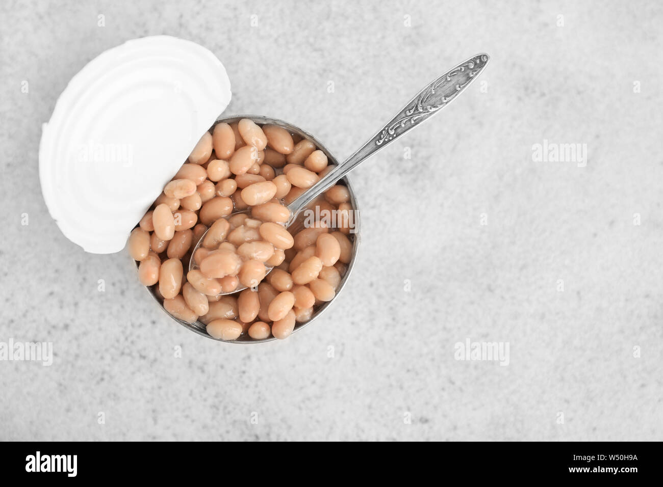 Tin can with beans on grey background Stock Photo - Alamy