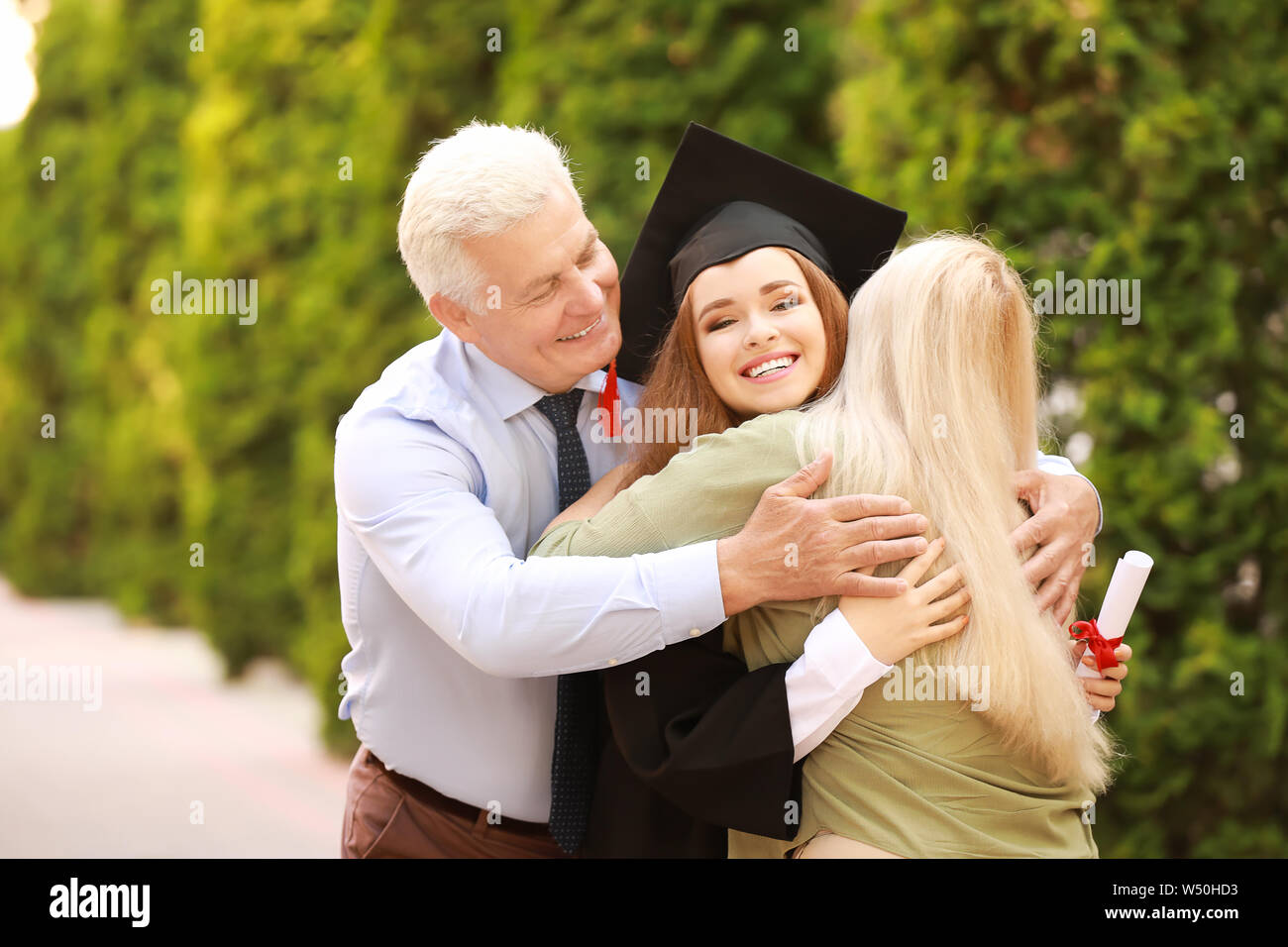 Happy young woman with diploma and her parents on graduation day Stock ...