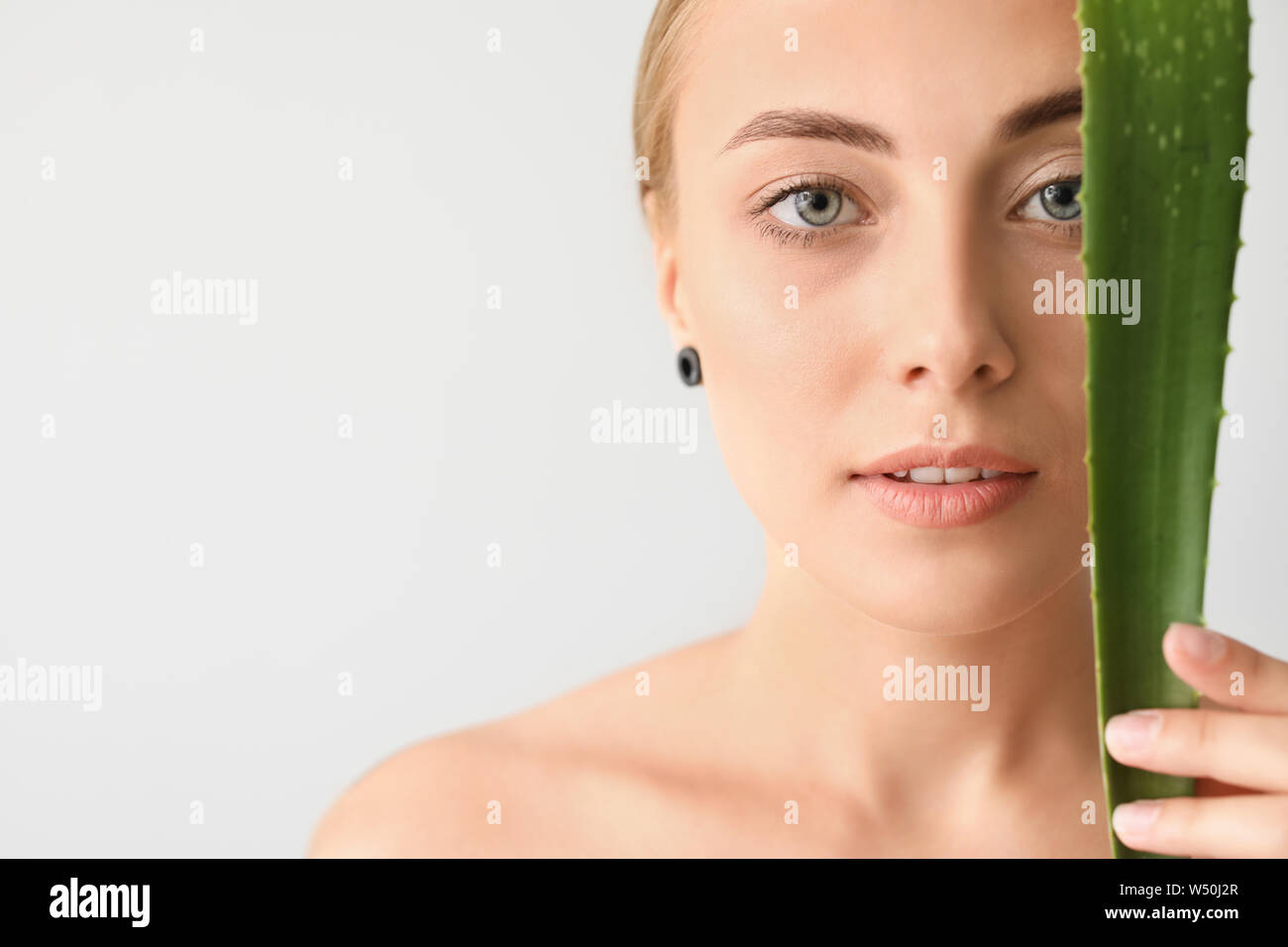 Beautiful young woman with aloe vera on light background Stock Photo ...
