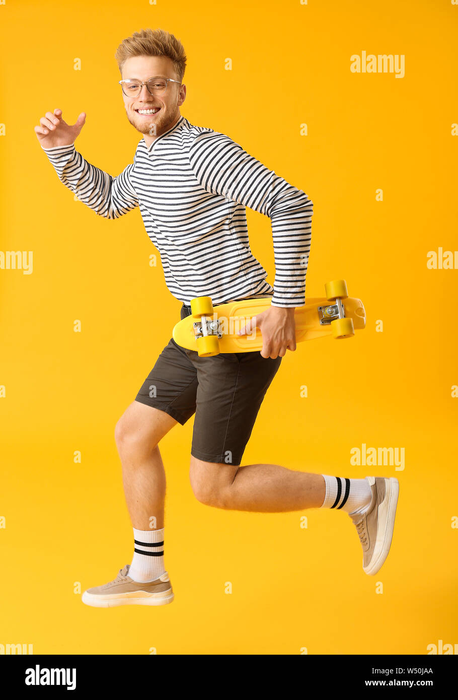 Stylish running young man with skateboard on color background Stock ...