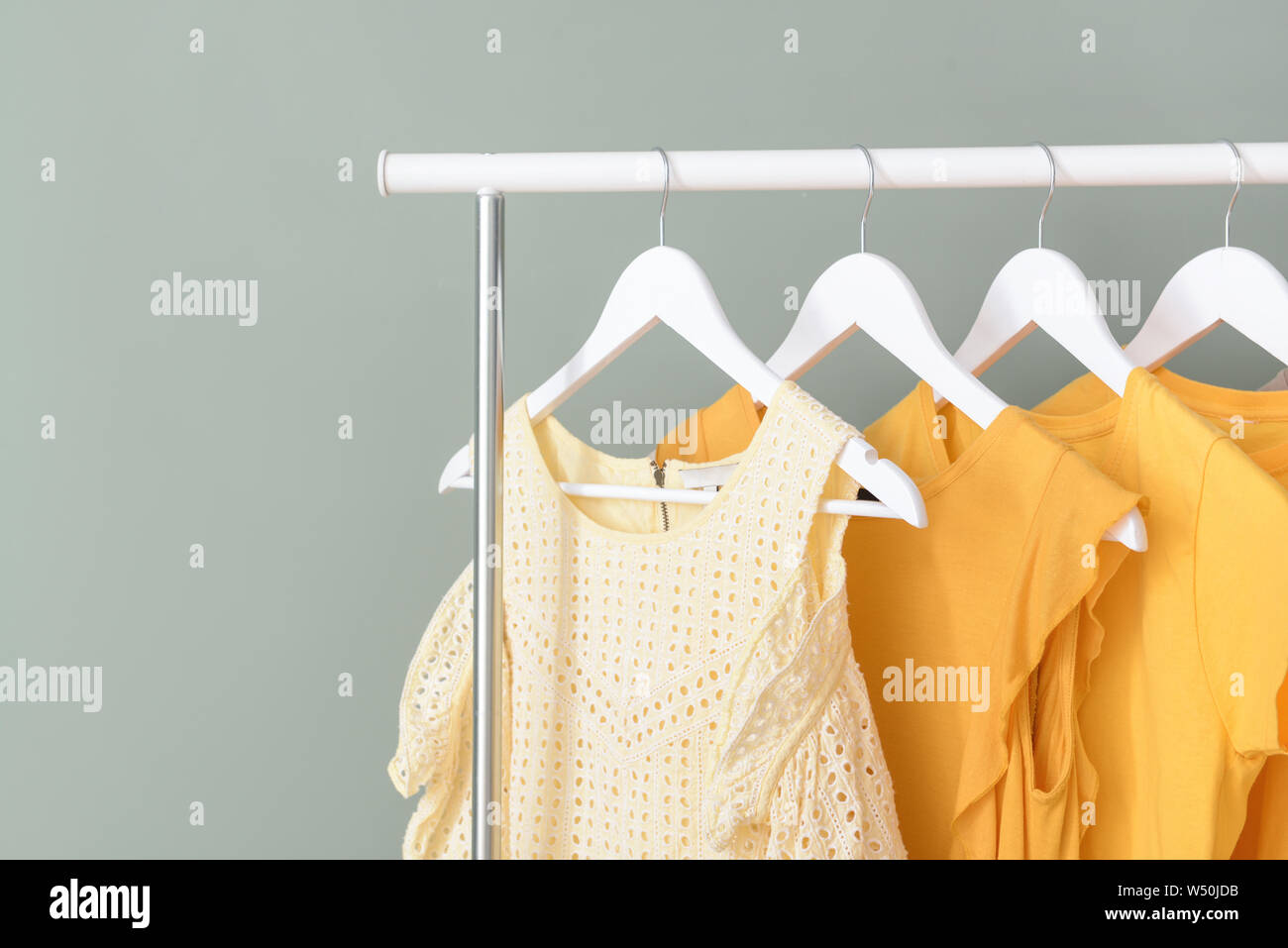 Rack with hanging clothes on color background Stock Photo - Alamy