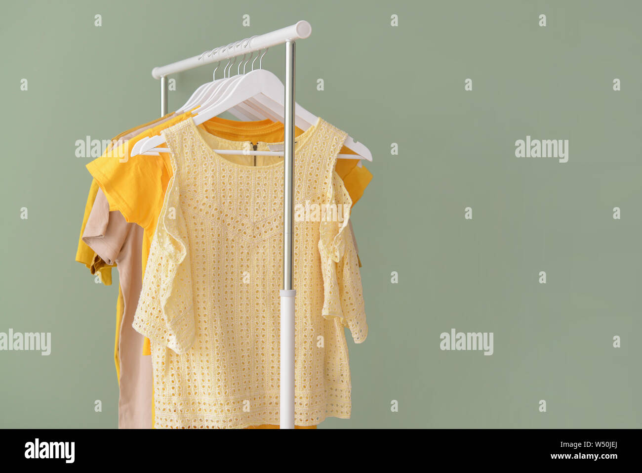 Rack with hanging clothes on color background Stock Photo - Alamy