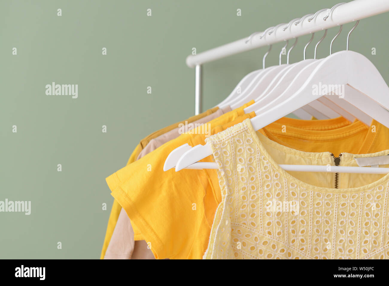Rack with hanging clothes on color background Stock Photo - Alamy