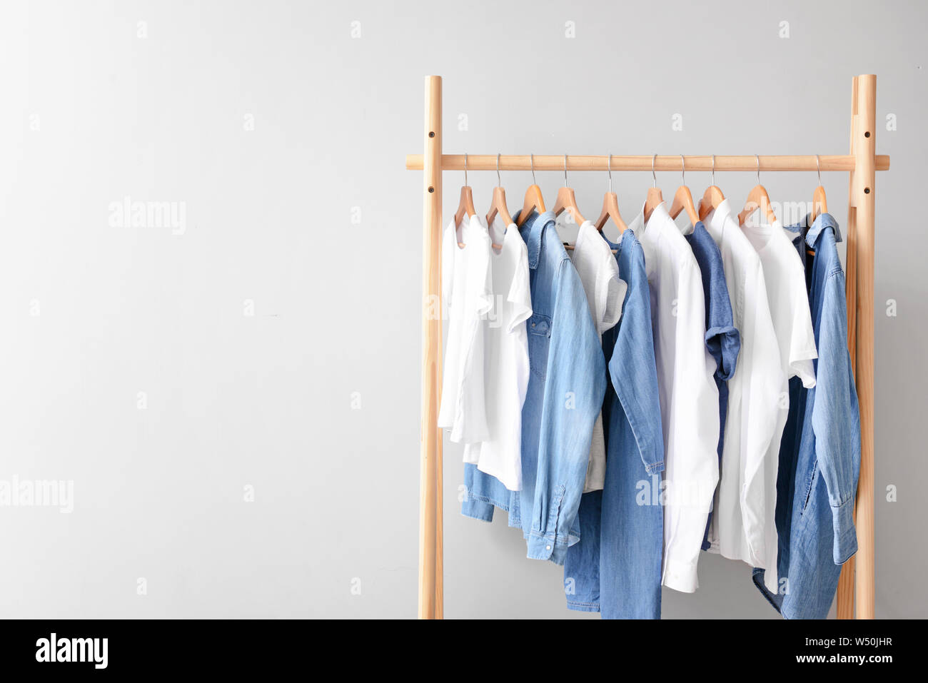 Rack with hanging clothes on light background Stock Photo - Alamy