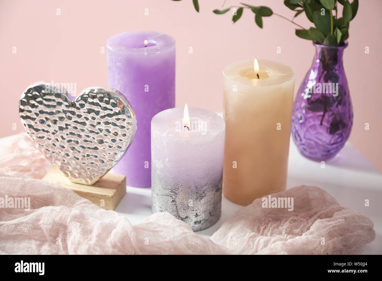 Beautiful burning candles on table against color background Stock Photo ...