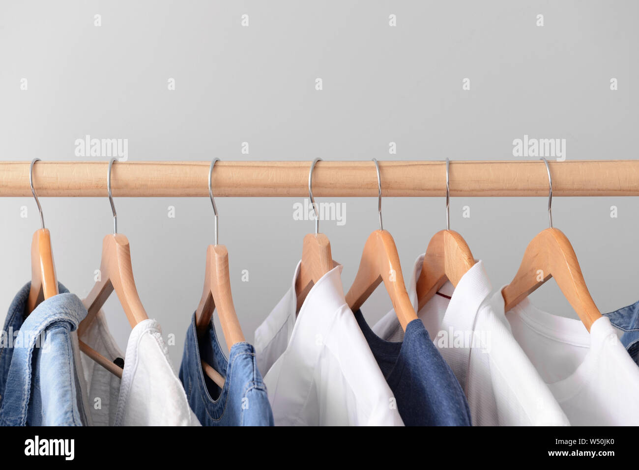 Rack with hanging clothes on light background Stock Photo - Alamy