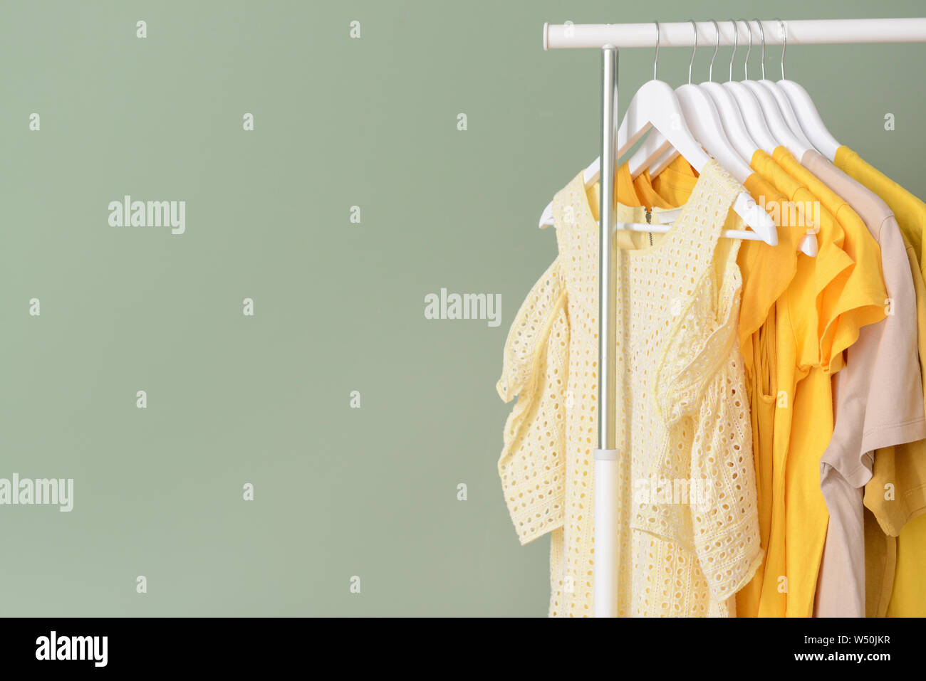 Rack with hanging clothes on color background Stock Photo - Alamy