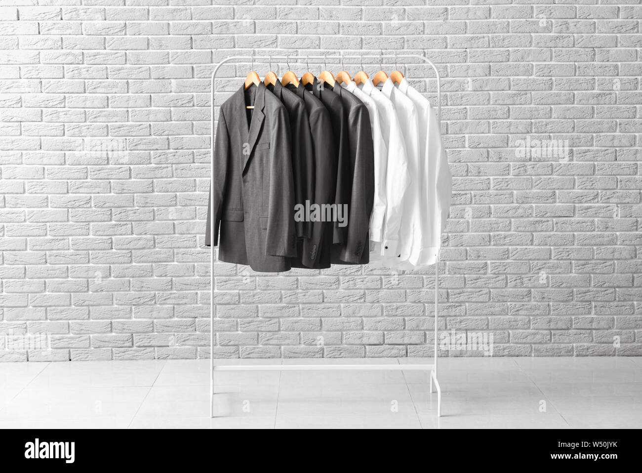 Rack with hanging clothes against brick wall Stock Photo - Alamy