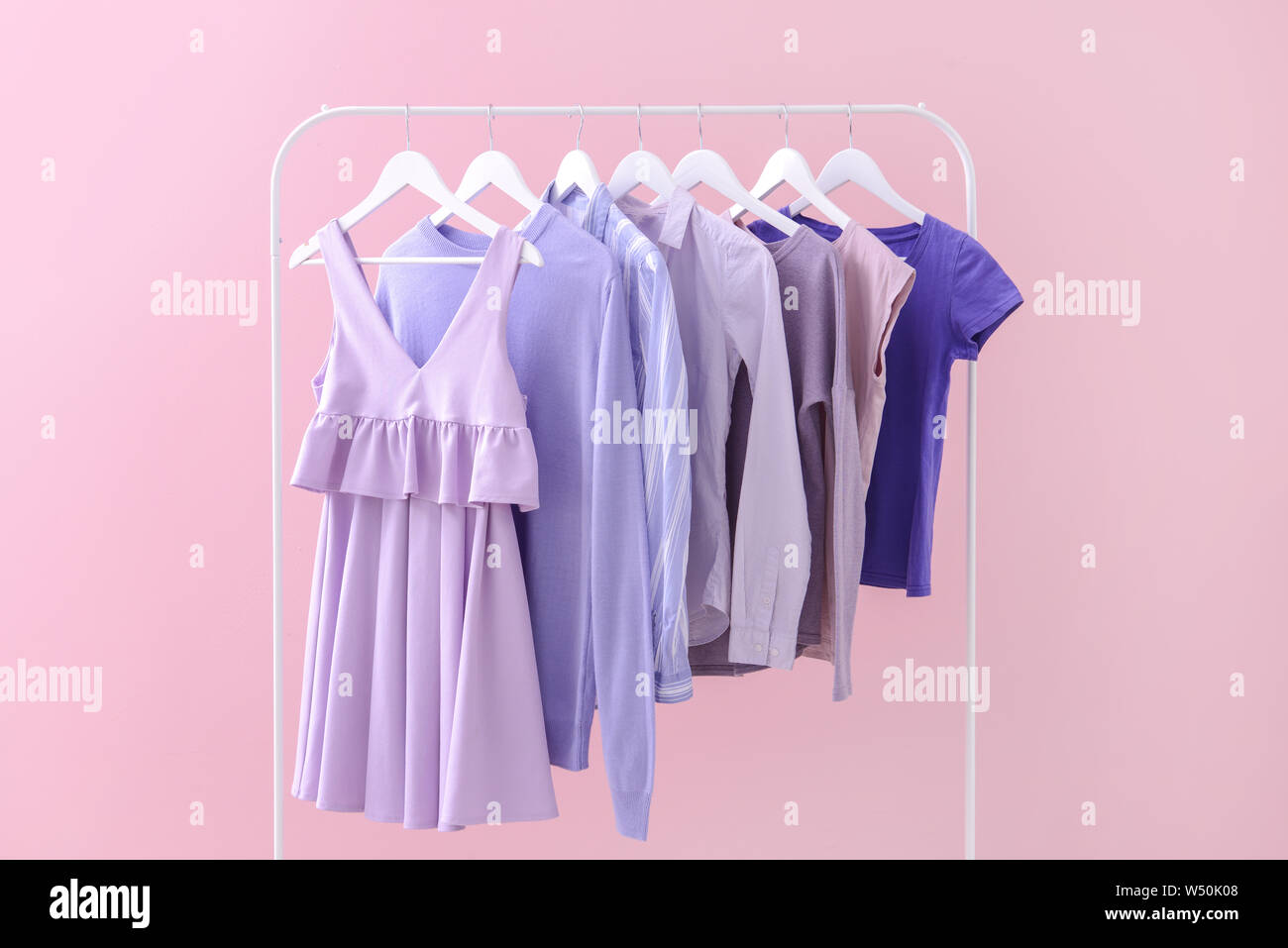 Rack with hanging clothes on color background Stock Photo - Alamy