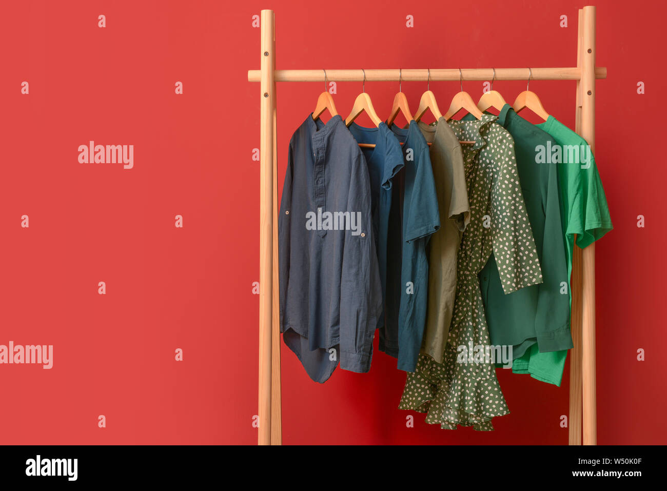 Rack with hanging clothes on color background Stock Photo - Alamy