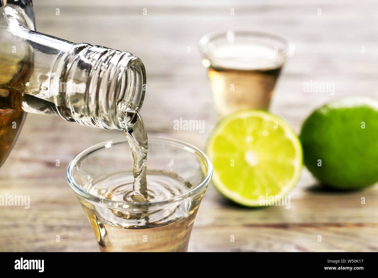 Pouring of tequila in glass on table Stock Photo - Alamy